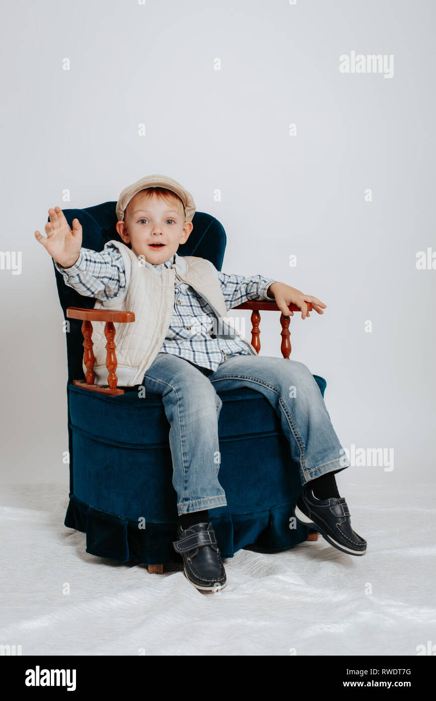 Little boy in a cap sits in an easy chair on a white background Stock ...