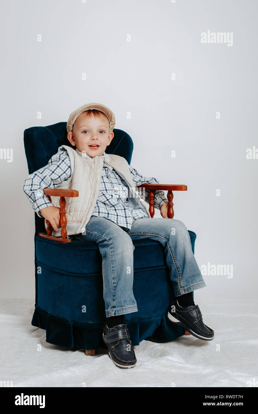 Little boy in a cap sits in an easy chair on a white background Stock ...