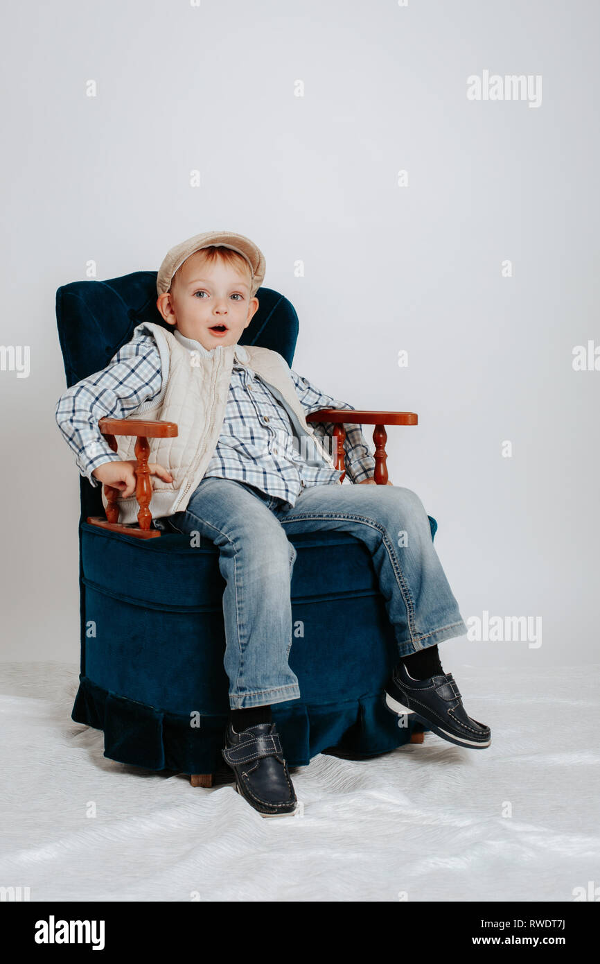 Little boy in a cap sits in an easy chair on a white background Stock ...