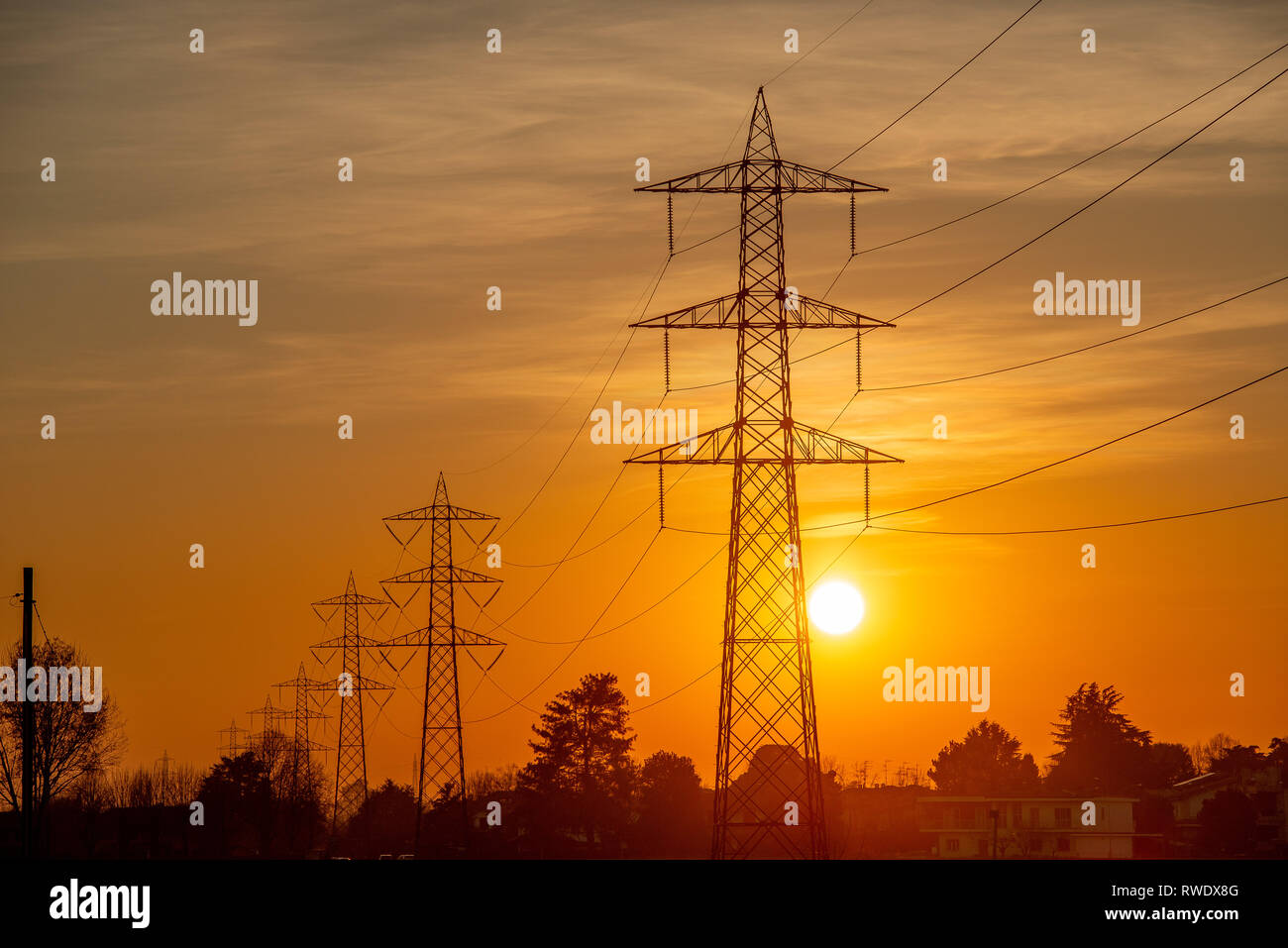 high voltage pylons against the light at sunset Stock Photo - Alamy
