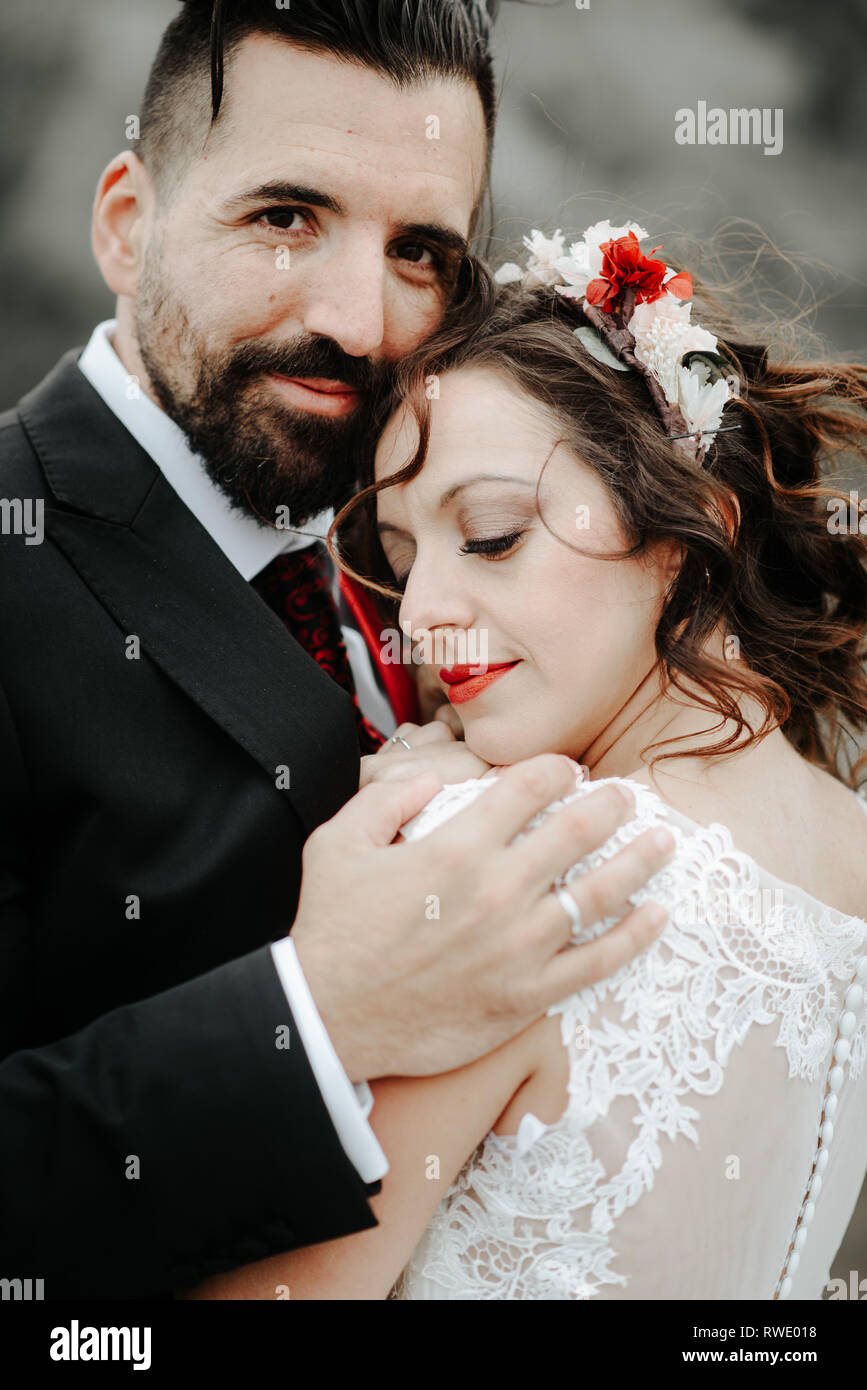 The bride and groom leaned against each other. They look at the camera ...
