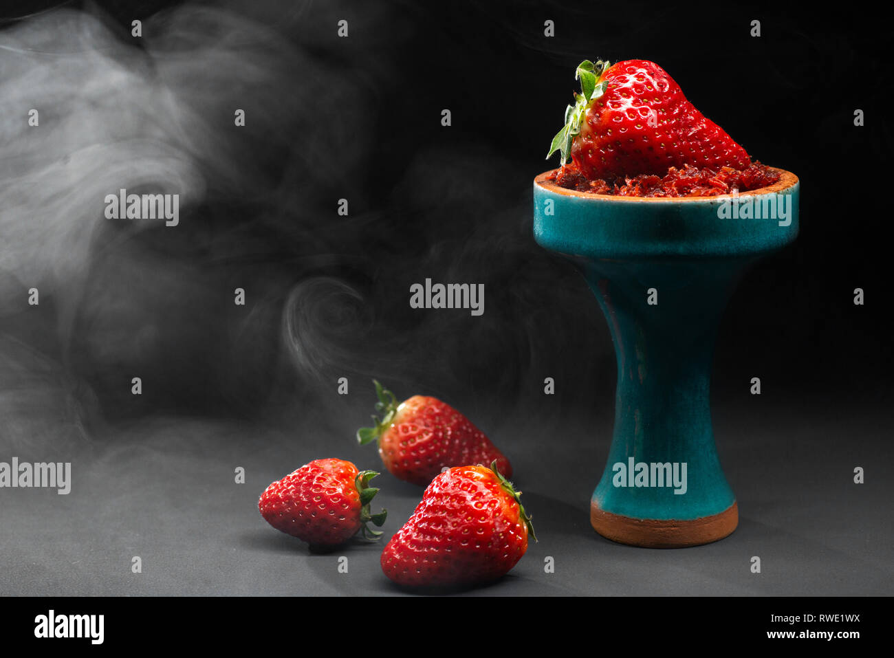 Hookah head with fruit on it decorated with exhaled smoke on black ...