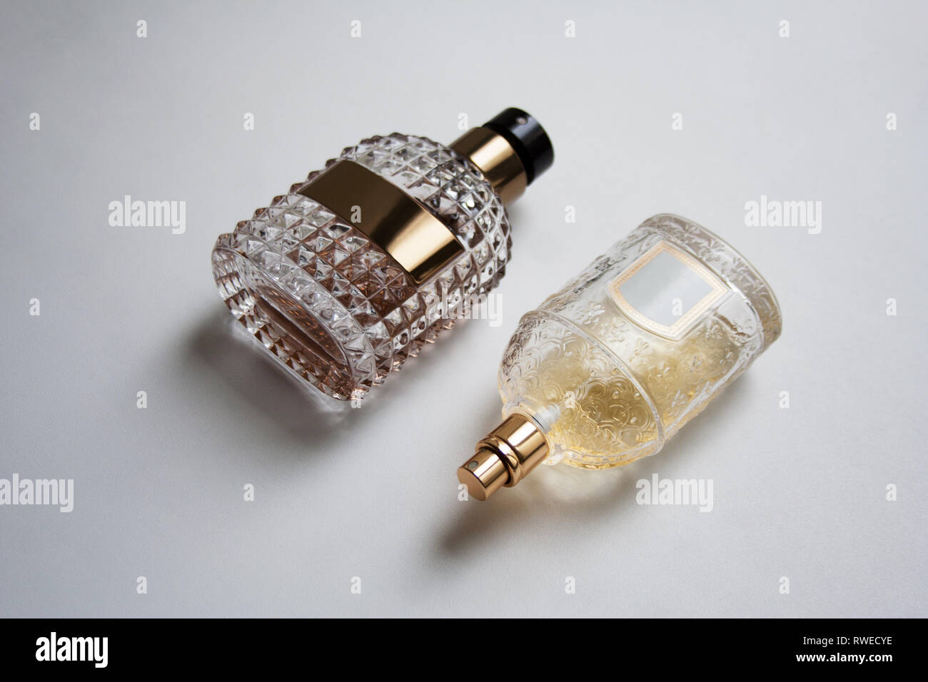 Two textured glass perfume bottles with glossy golden details isolated ...