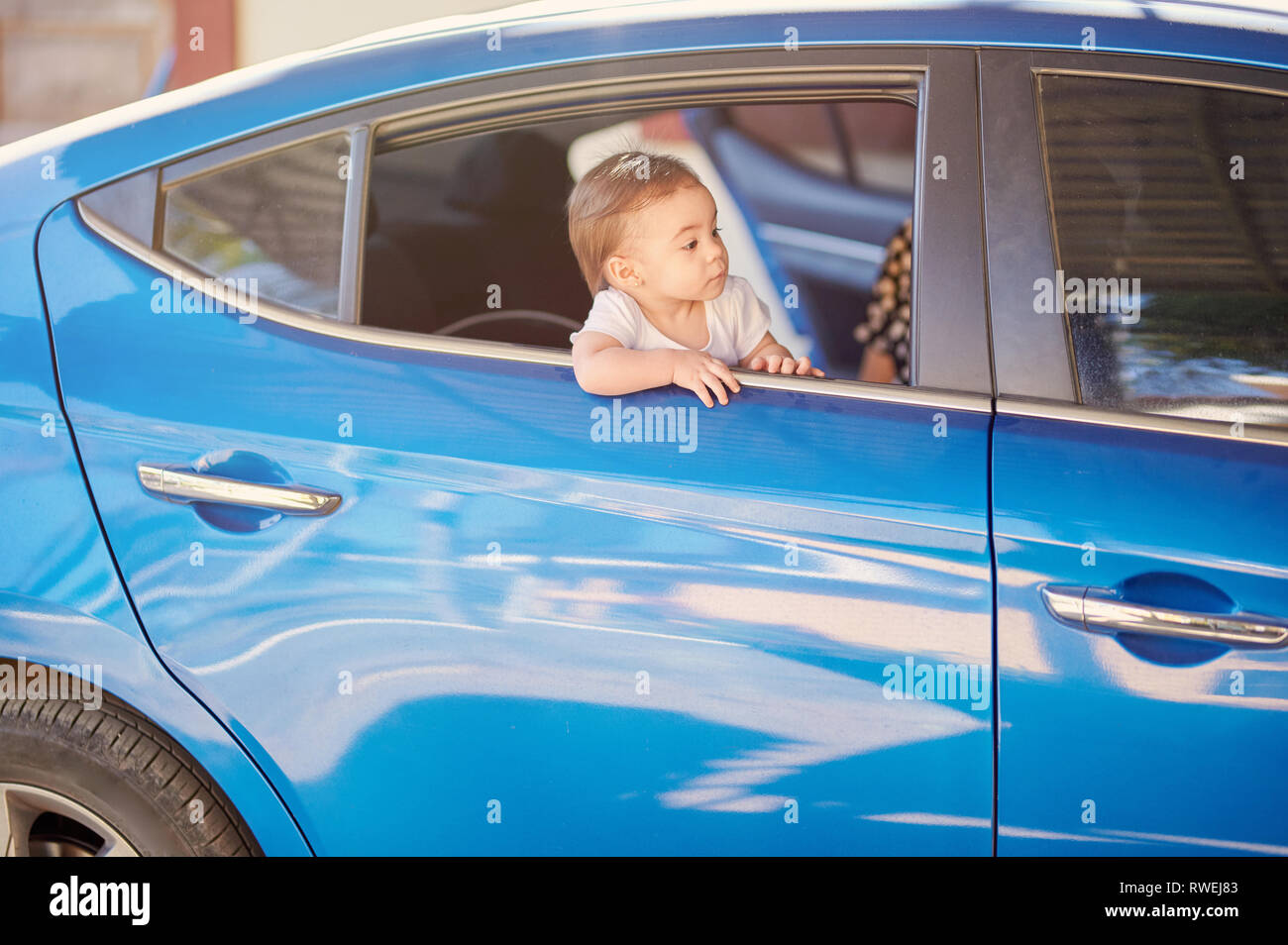 Baby ready to go on car. Looking from car window baby girl Stock Photo ...