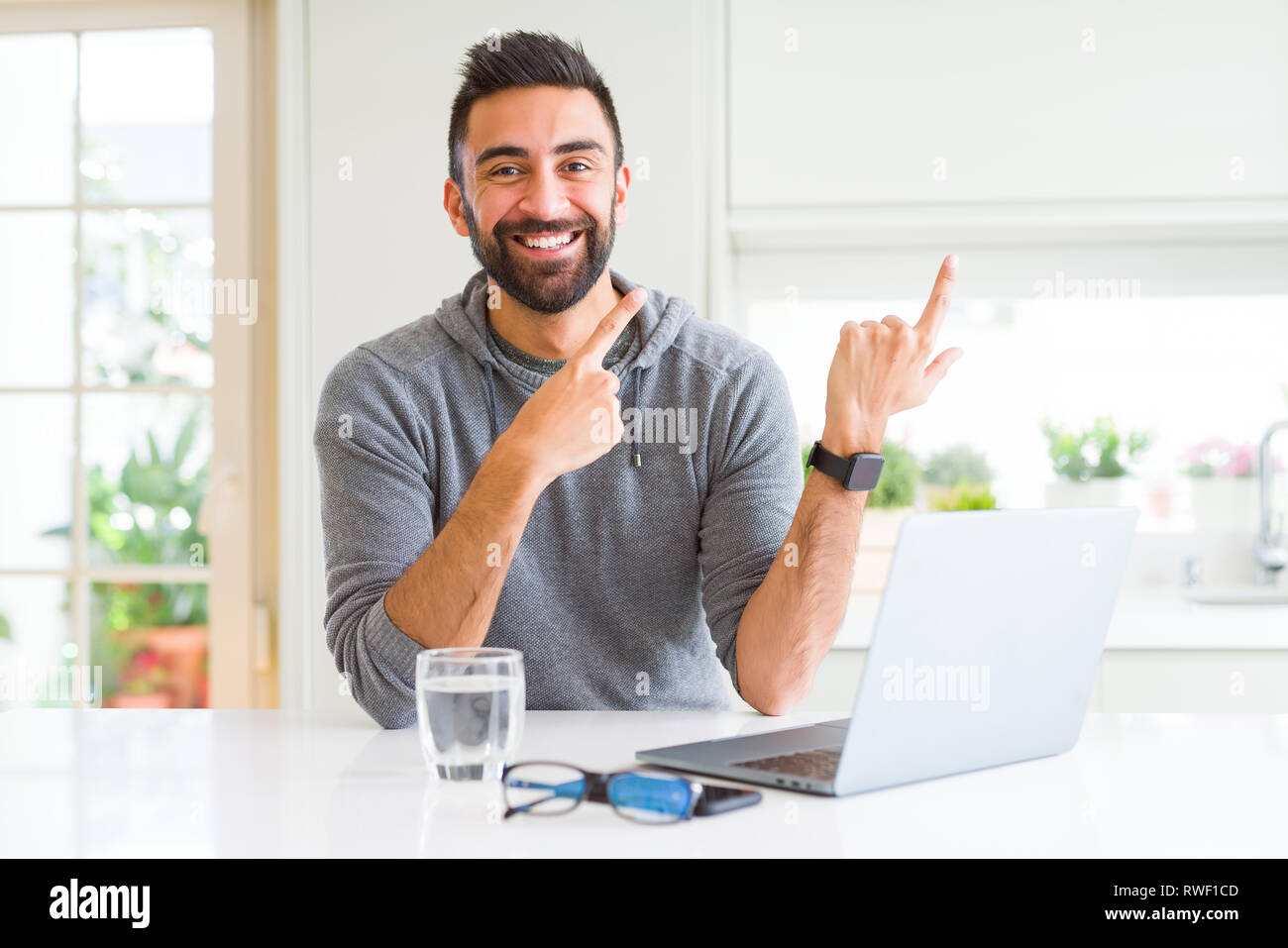 Handsome hispanic man working using computer laptop smiling and looking ...