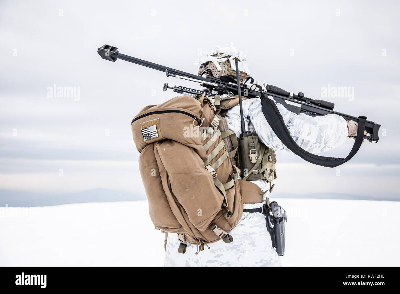 Rear view of an Army soldier with sniper rifle in action in the arctic ...