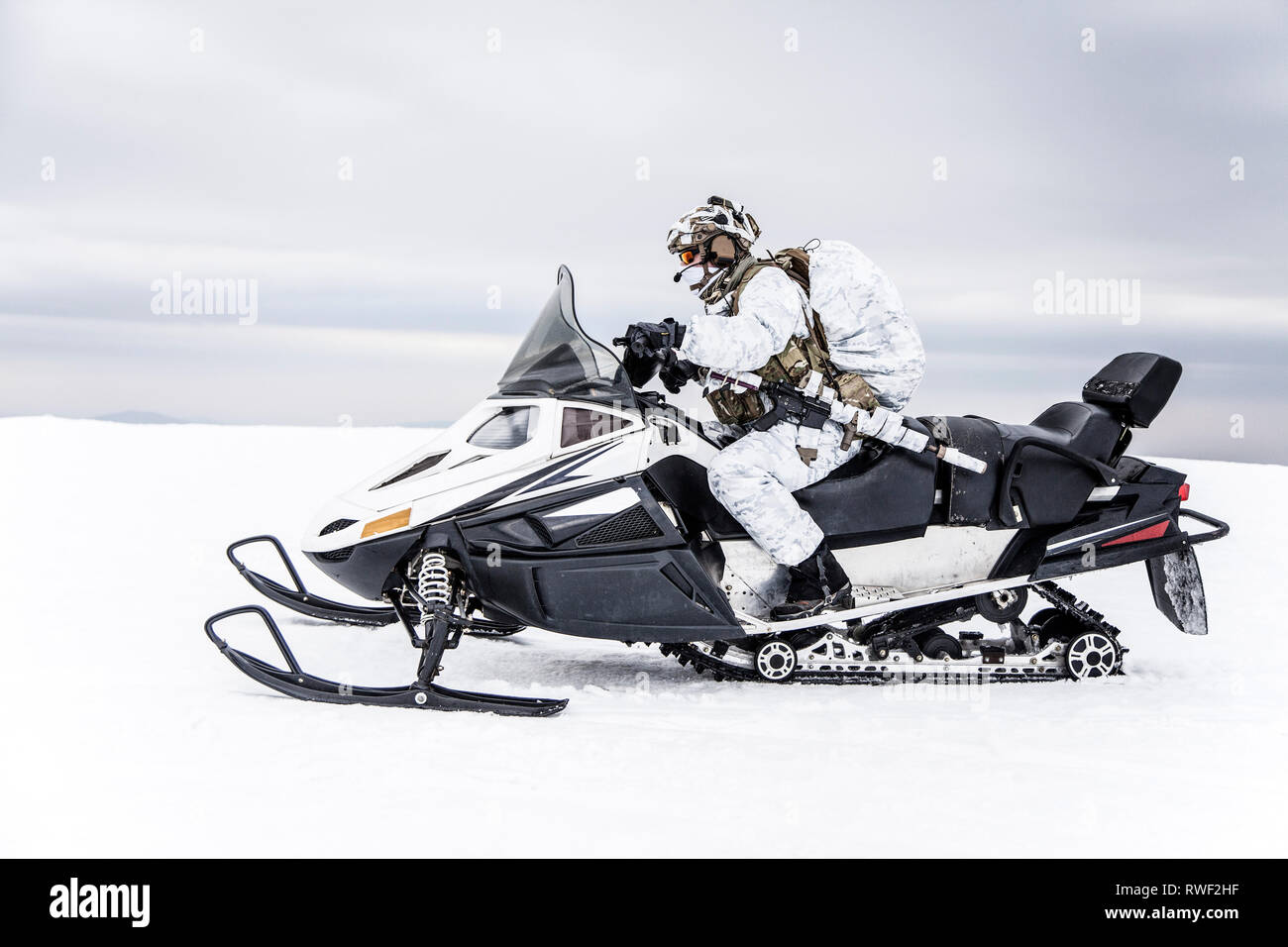 Army soldier in winter camo driving a tracked snowmobile somewhere in ...