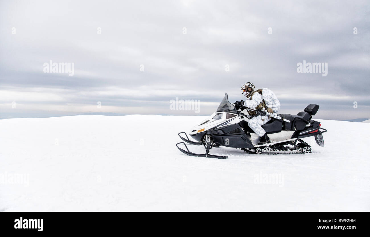 Army soldier in winter camo driving a tracked snowmobile somewhere in ...