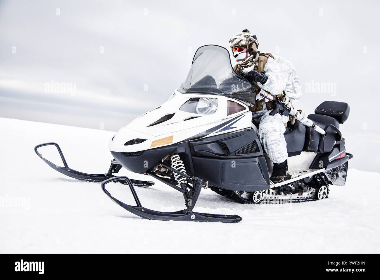 Army soldier in winter camo driving a tracked snowmobile somewhere in ...
