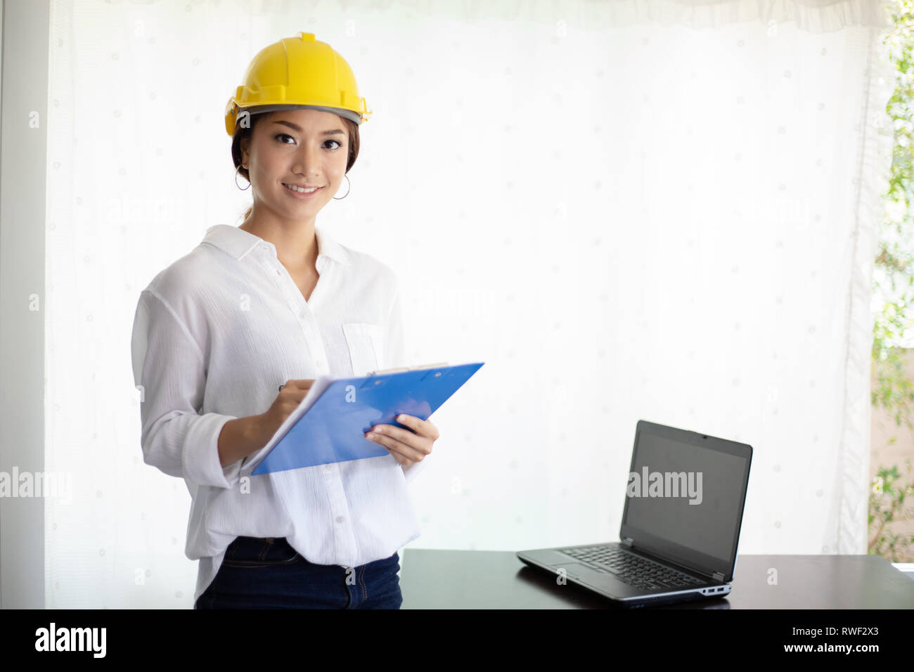 Asian women engineering inspecting and working and holding blueprints ...