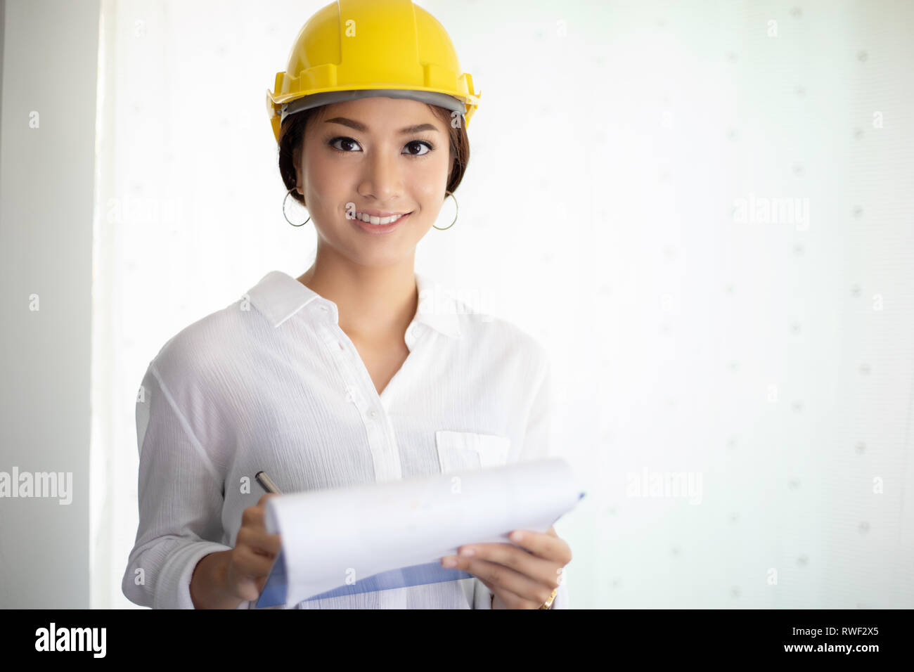 Asian women engineering inspecting and working and holding blueprints ...