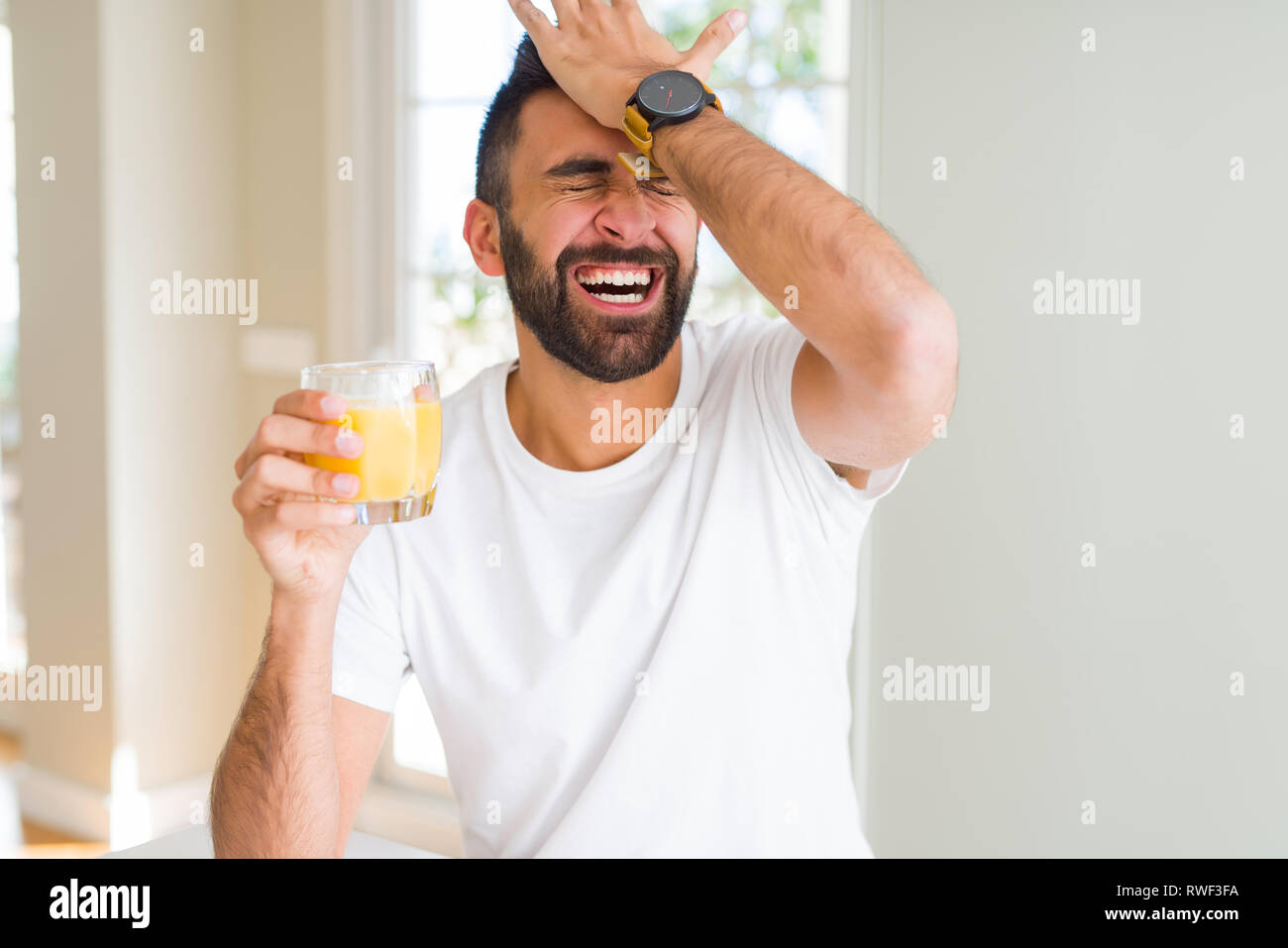 Handsome hispanic man drinking healthy orange juice stressed with hand ...