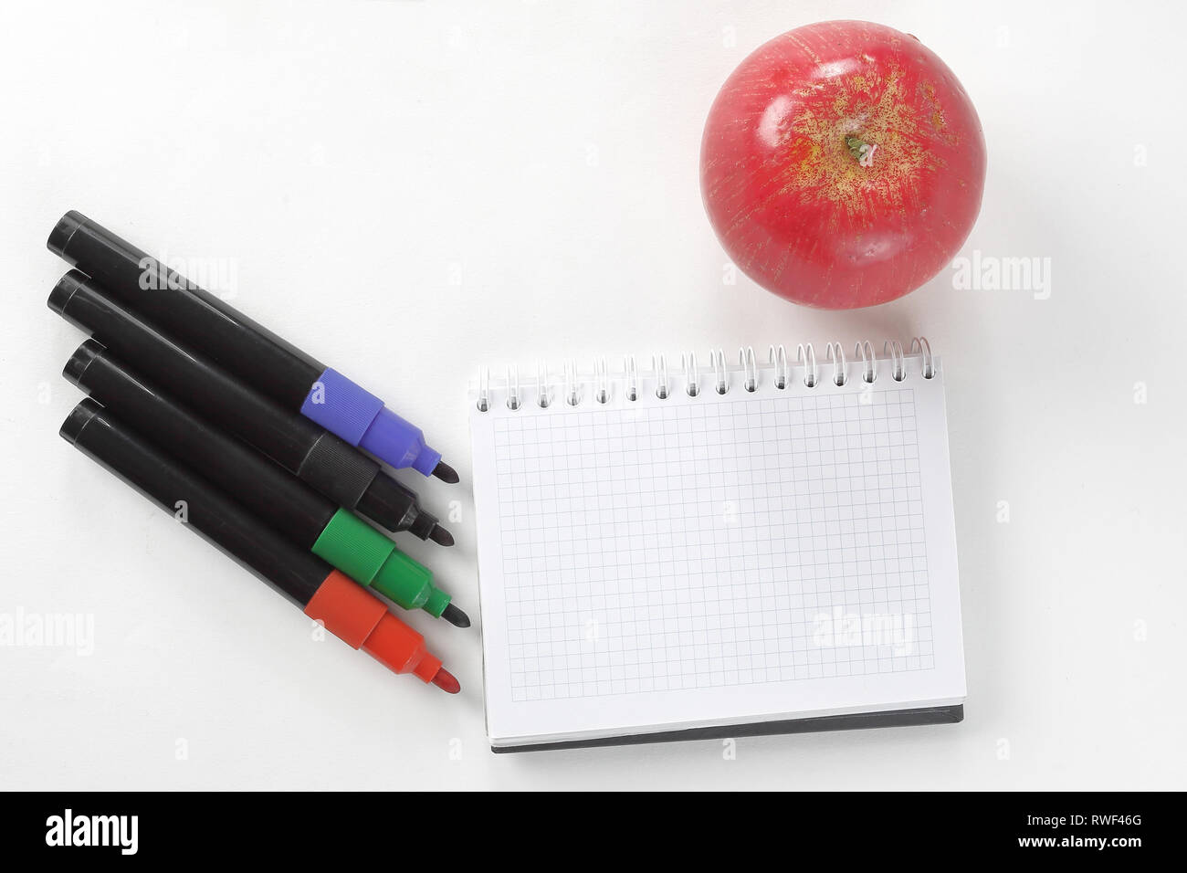 Apple, multicolored markers and open Notepad isolated on white ...