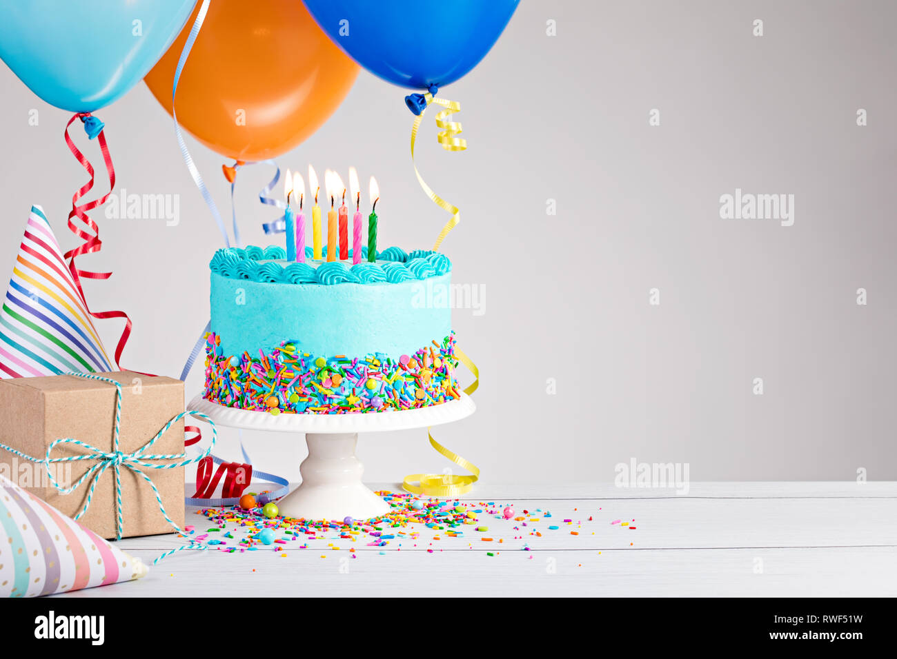 Blue Birthday Cake With Lit Candles Presents Hats And Colorful