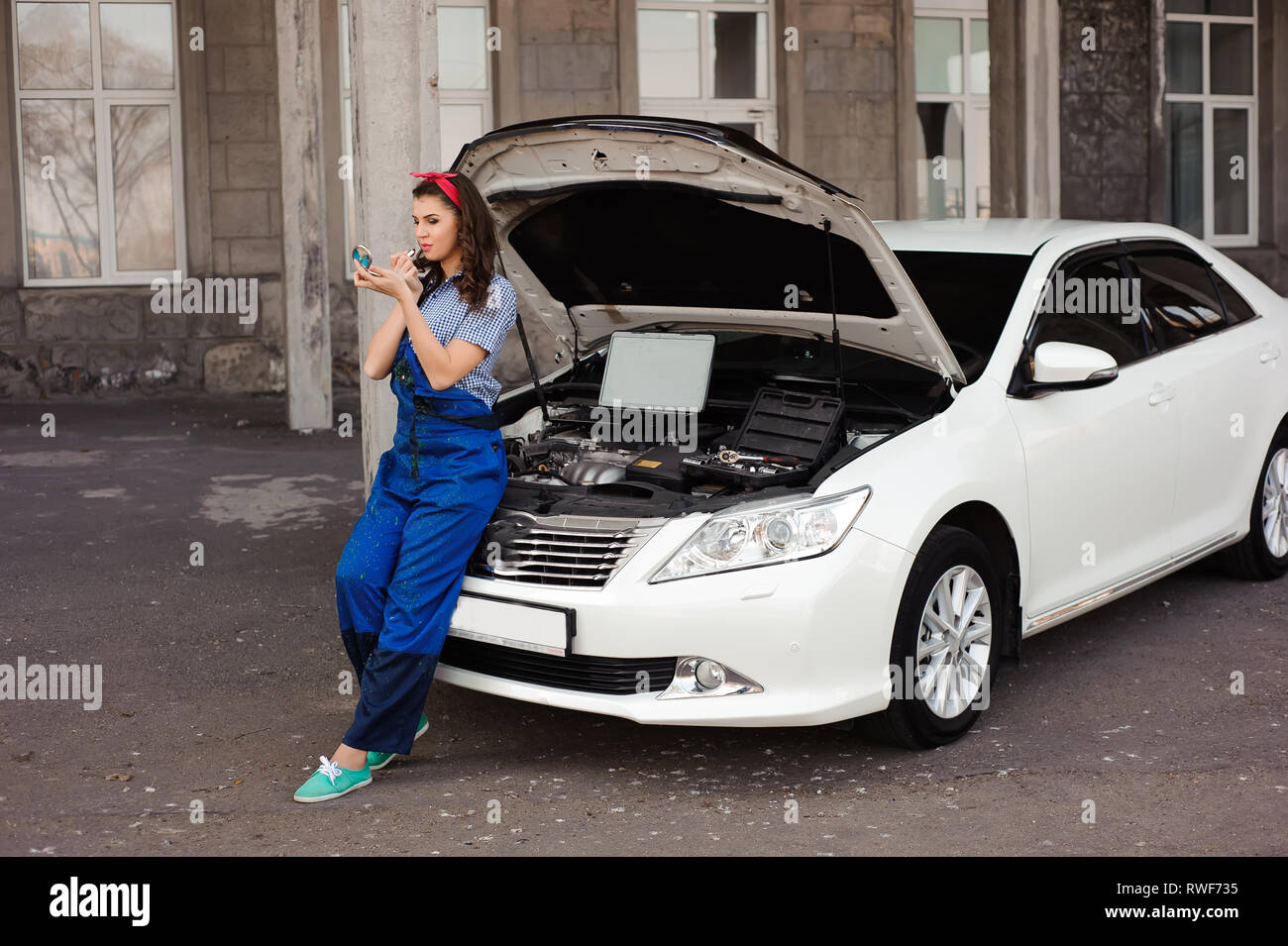 Cute attractive girl examining car engine at the auto repair shop Stock ...