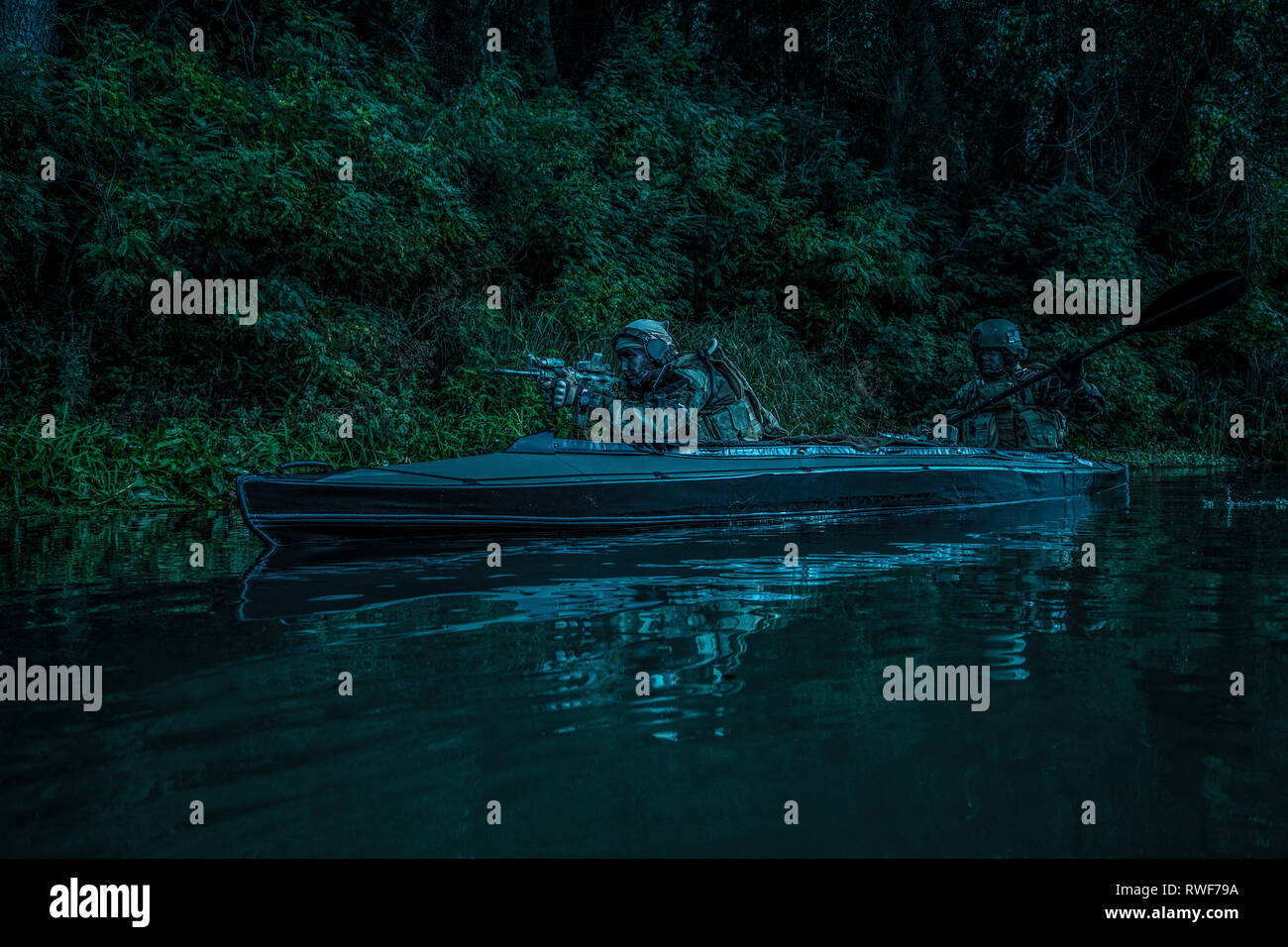 Special forces men paddling Army kayak across the river at twilight ...