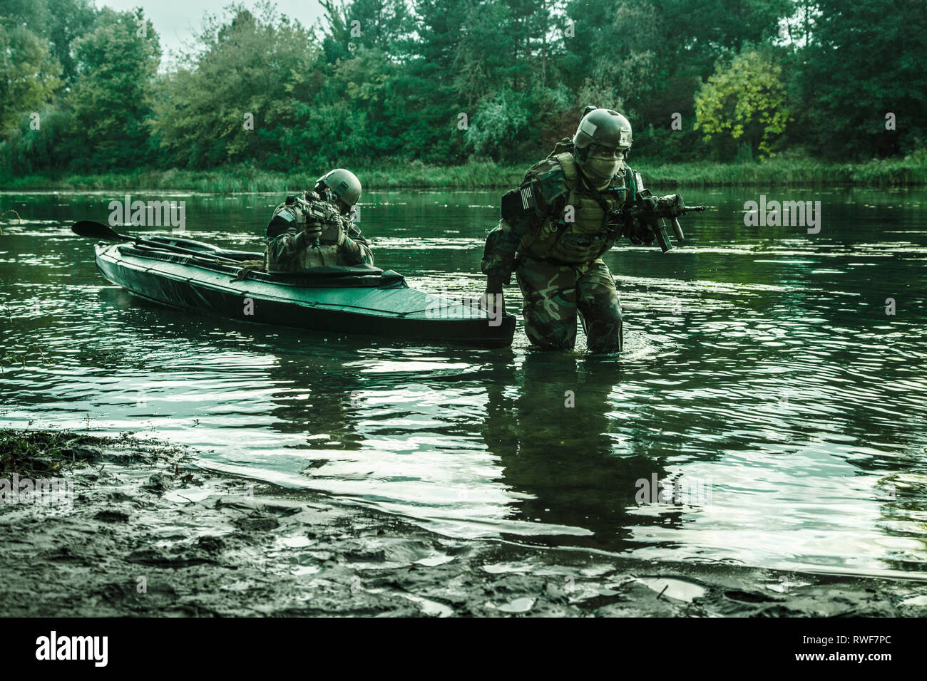 Pair of soldiers disembarking from their military kayak under the cover ...
