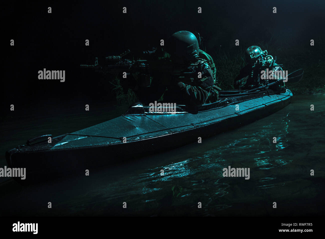 Two special forces soldiers in a military kayak under cover of darkness ...