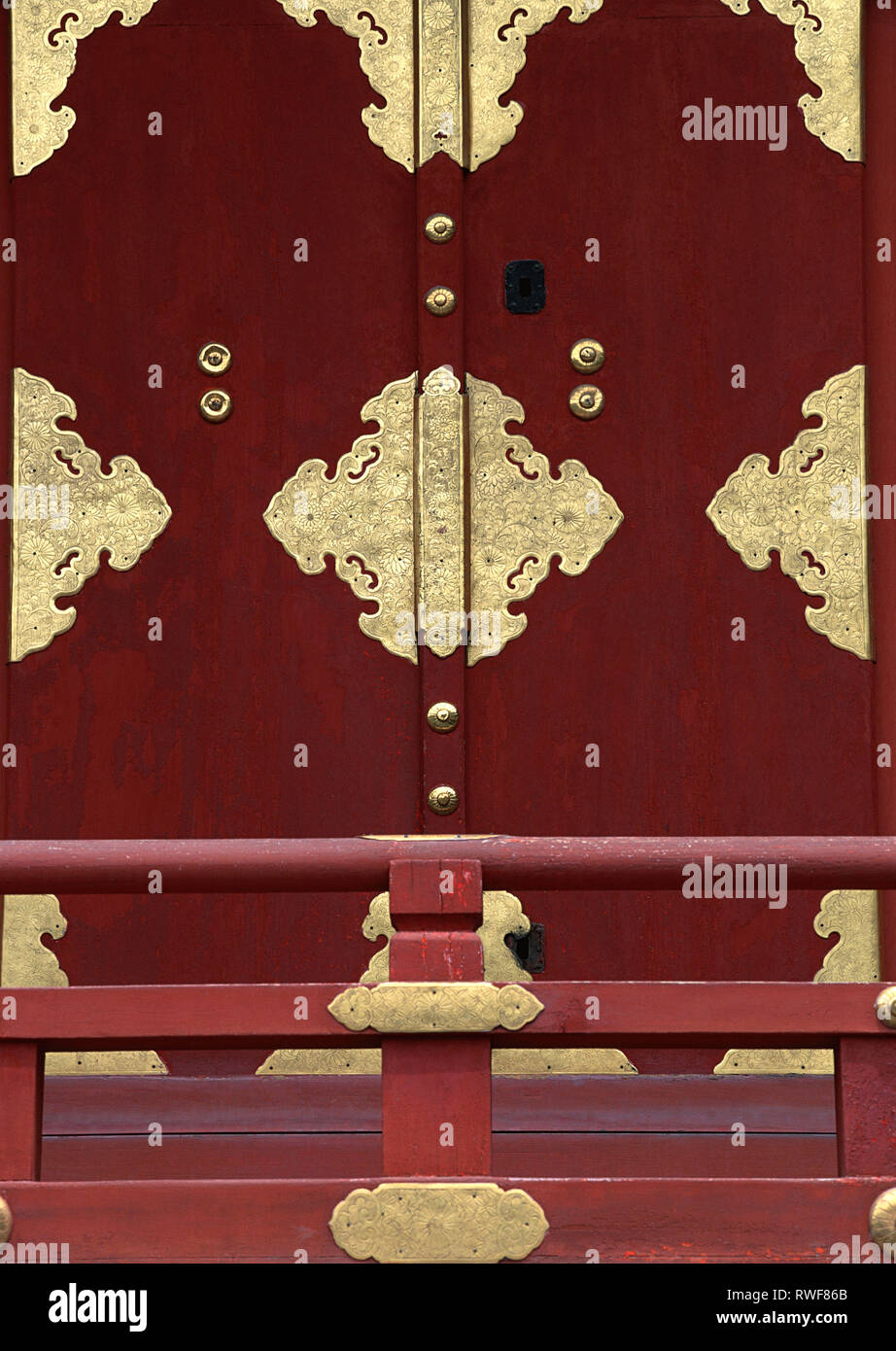 A Japanese red door with gold details and railings in front background ...