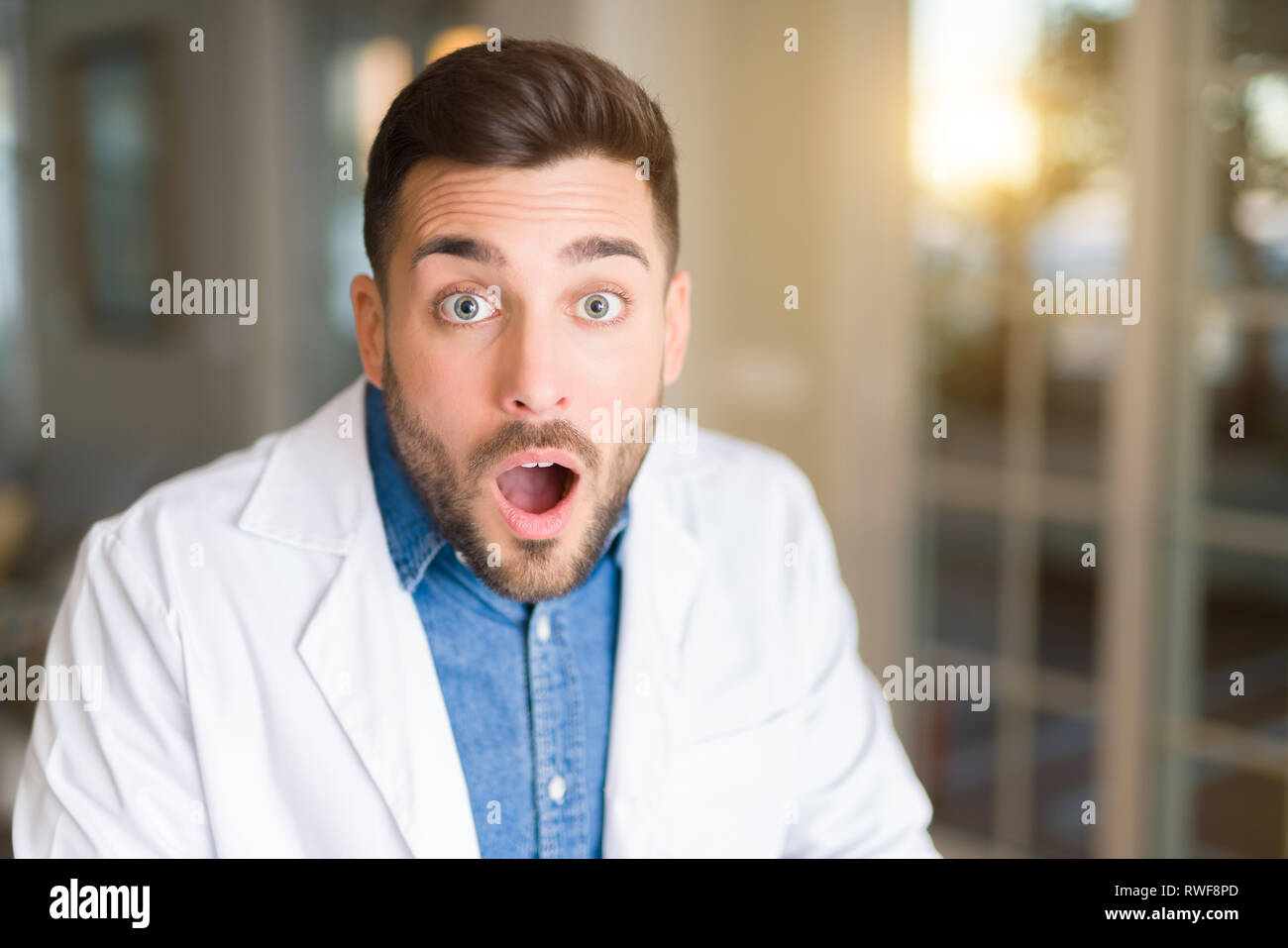 Young handsome doctor man at the clinic afraid and shocked with ...