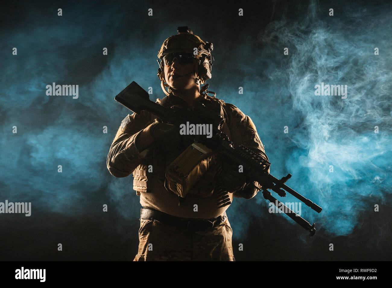 Army soldier in combat uniform with machine gun, dark smoke background ...