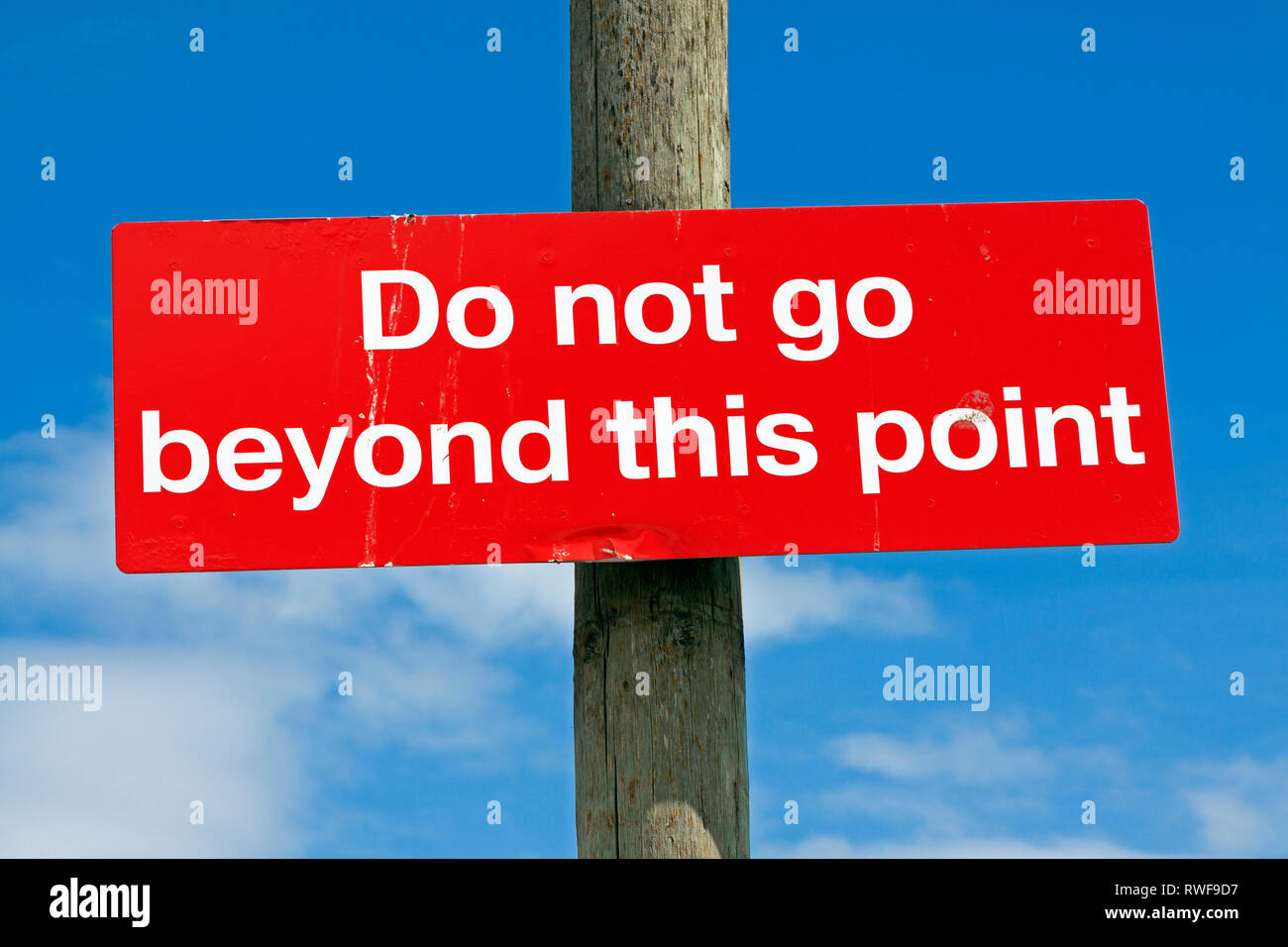 A sign reading “Do not go beyond this point” seen against a blue sky ...