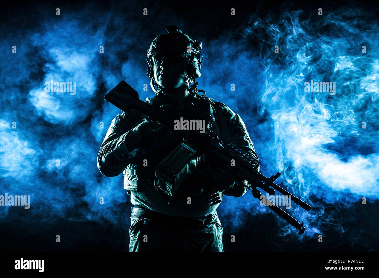 Army soldier in combat uniform with machine gun, dark smoke background ...