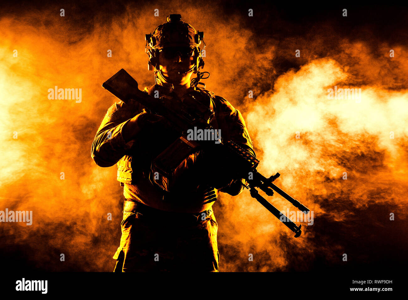 Army soldier in combat uniform with machine gun, fiery smoke background ...