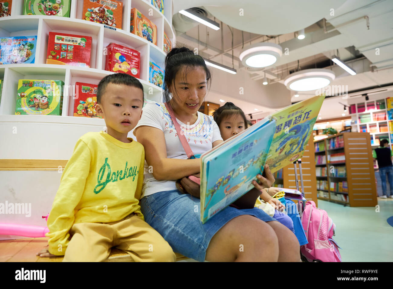 SHENZHEN, CHINA - SEPTEMBER 09, 2016: woman with children read book at ...