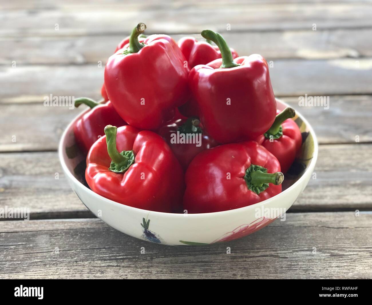 Three sweet red peppers on the brown wooden table. Country style Stock ...