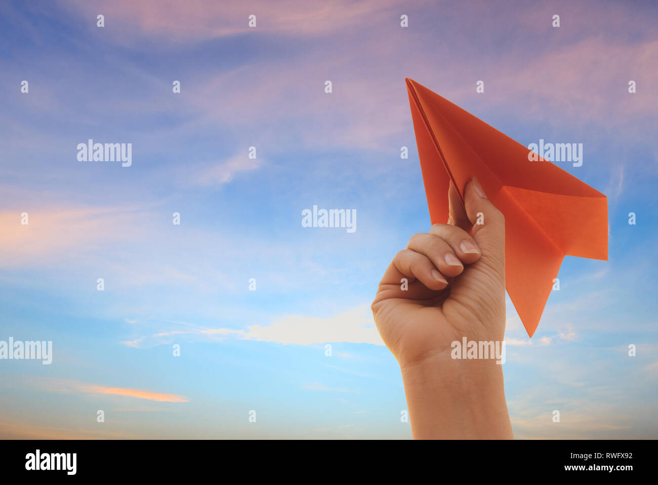 Woman Hand holding red paper rocket with blue sky background. freedom ...