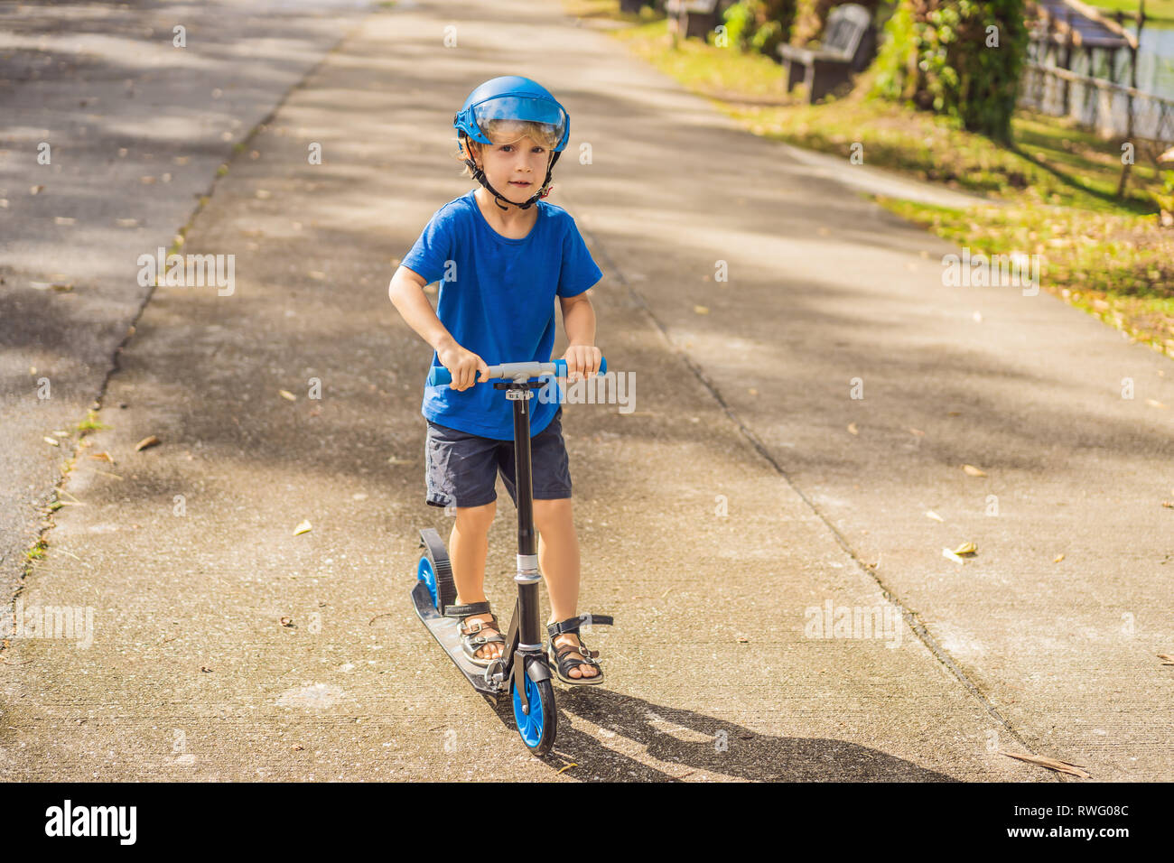 Boy riding scooters, outdoor in the park, summertime. Kids are happy ...