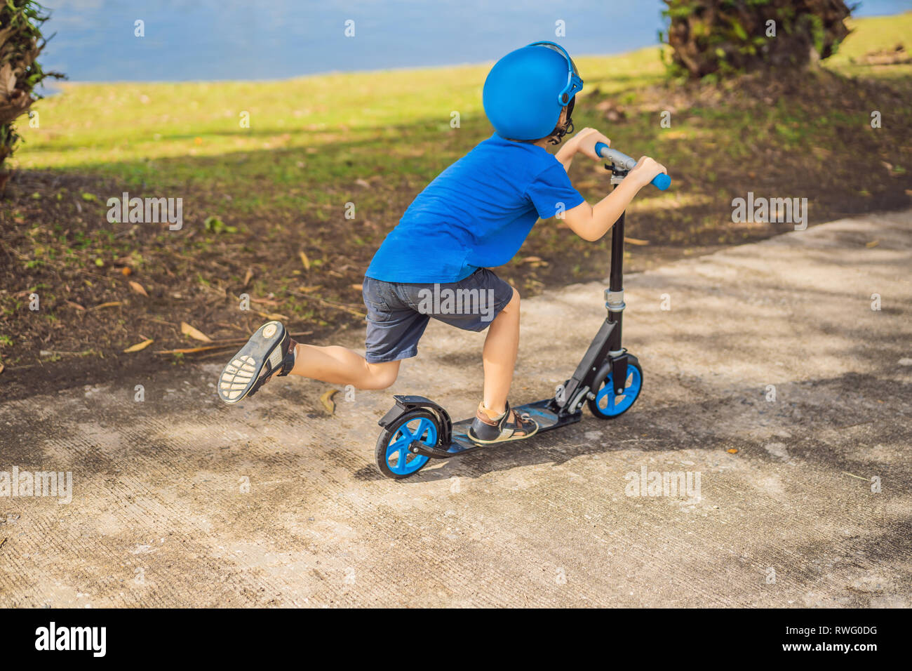 Boy riding scooters, outdoor in the park, summertime. Kids are happy ...