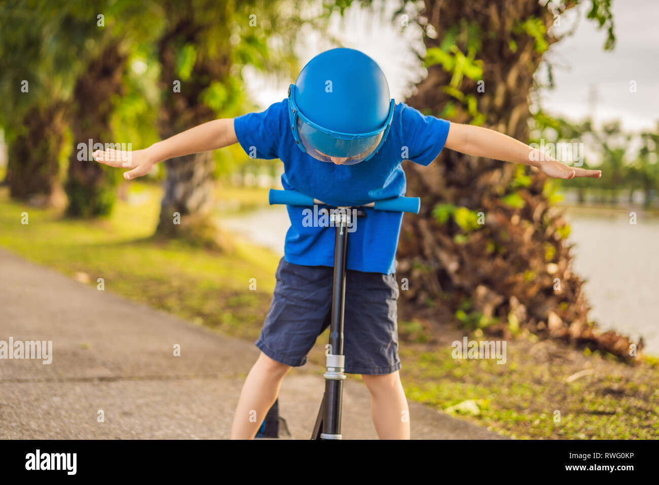 Boy riding scooters, outdoor in the park, summertime. Kids are happy ...
