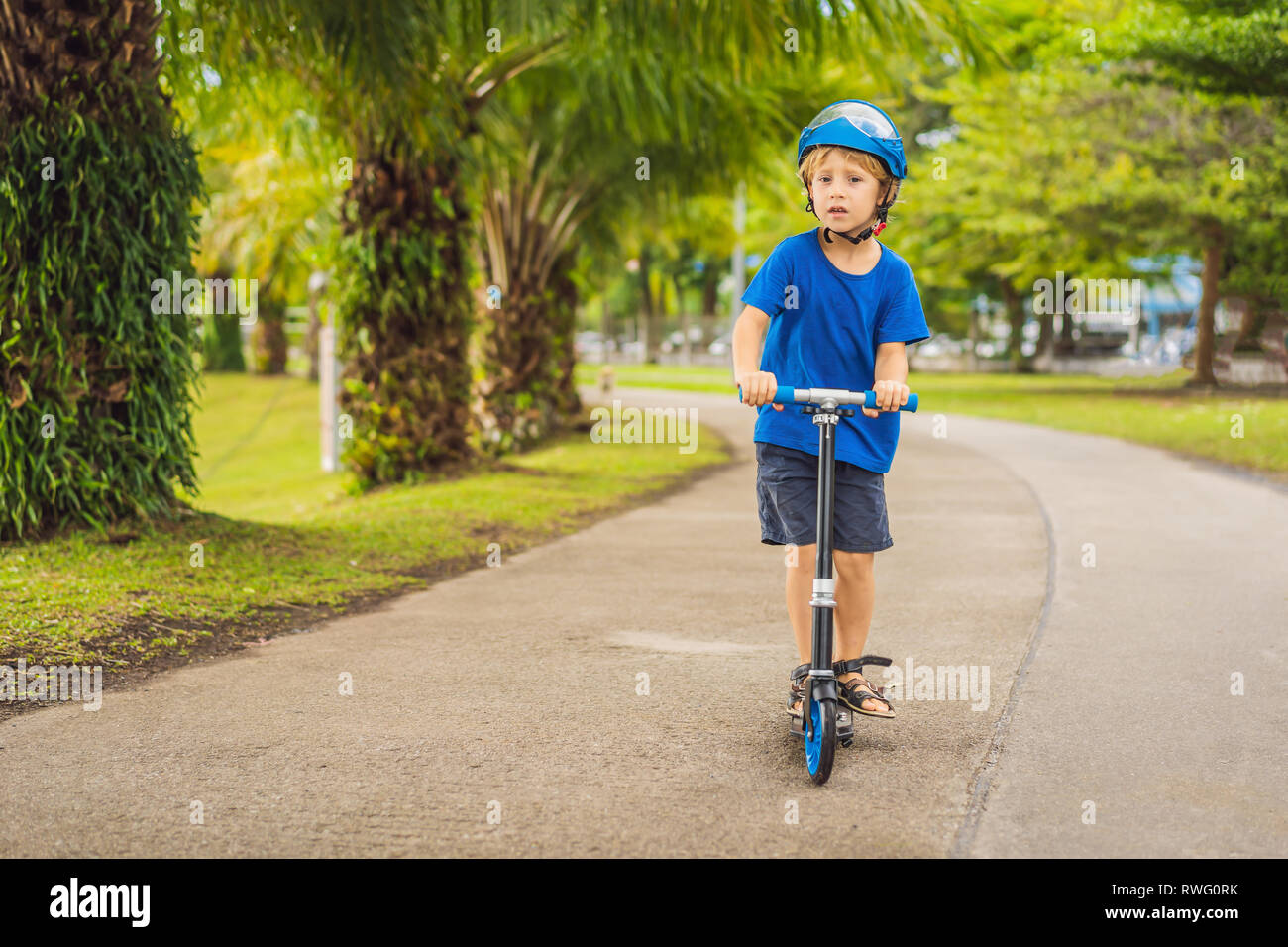 Boy riding scooters, outdoor in the park, summertime. Kids are happy ...