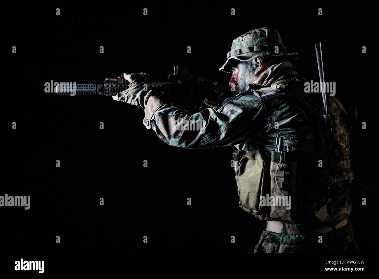 Backlit studio shot of a U.S. special forces soldier shooting his rifle ...