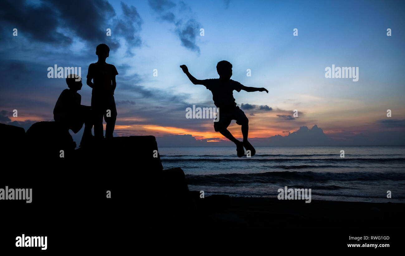 Jumping off the rocks standing by the beach rocks hi-res stock ...