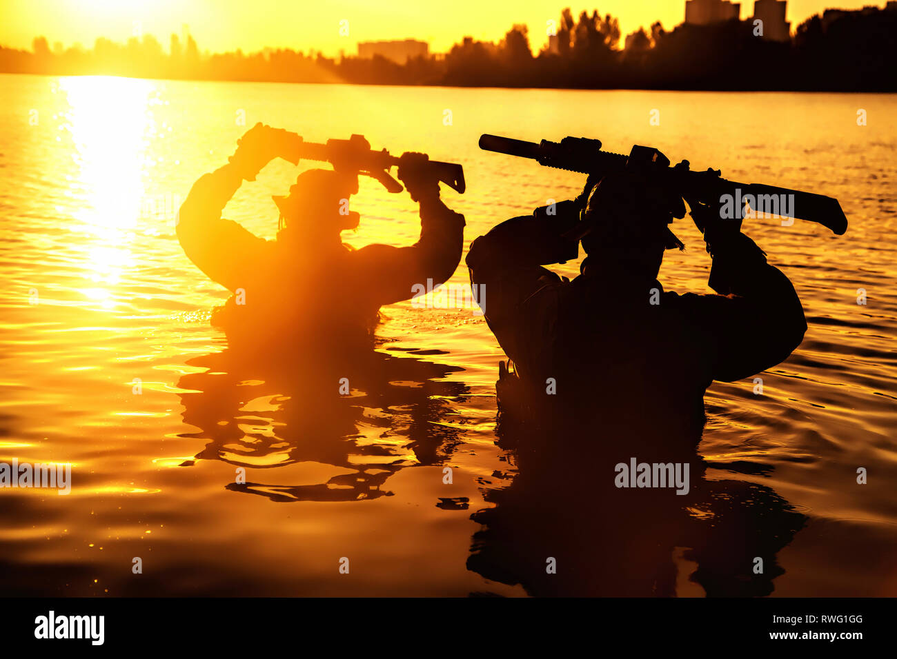 Special forces soldiers with rifles above head as they cross a river ...