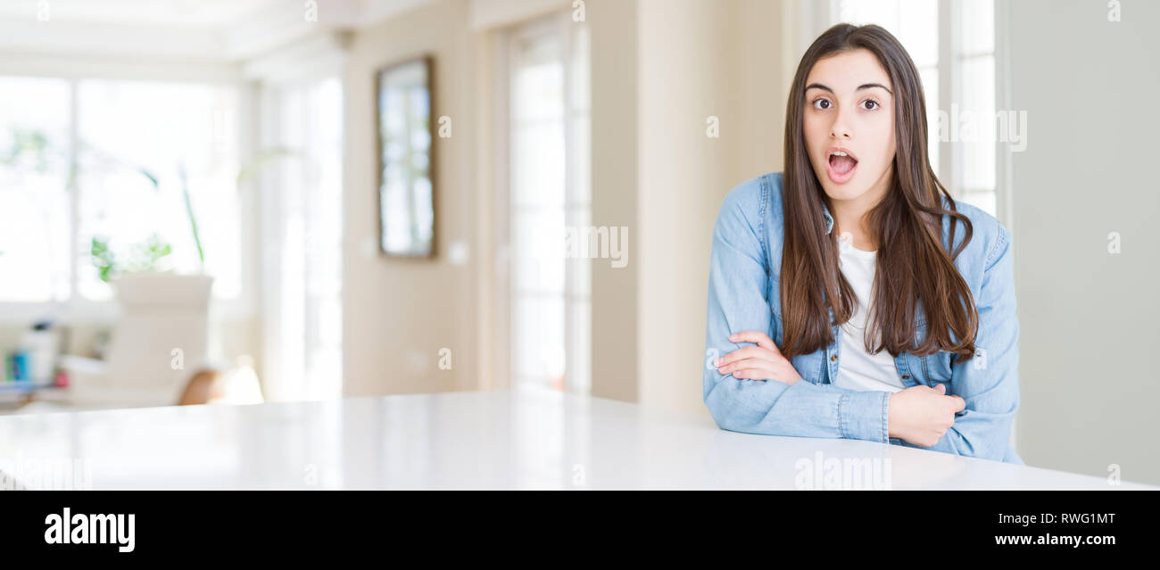 Wide angle picture of beautiful young woman sitting on white table at ...