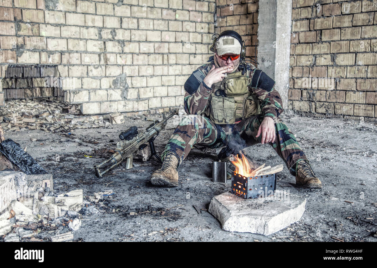 Special forces soldier smoking a cigarette while sitting by the fire in ...