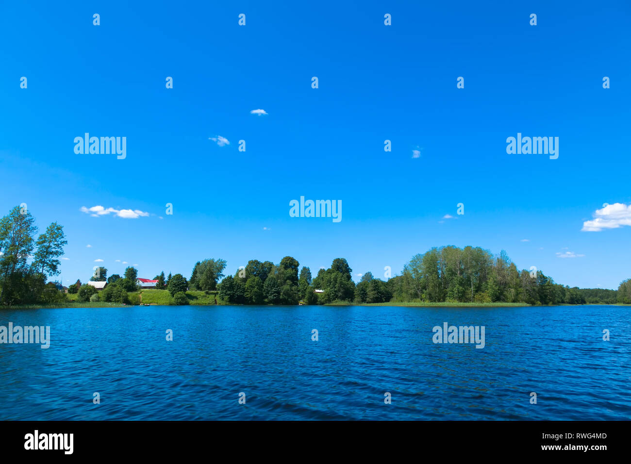 Blue sky and blue lake in summer. White clouds reflect in blue water ...