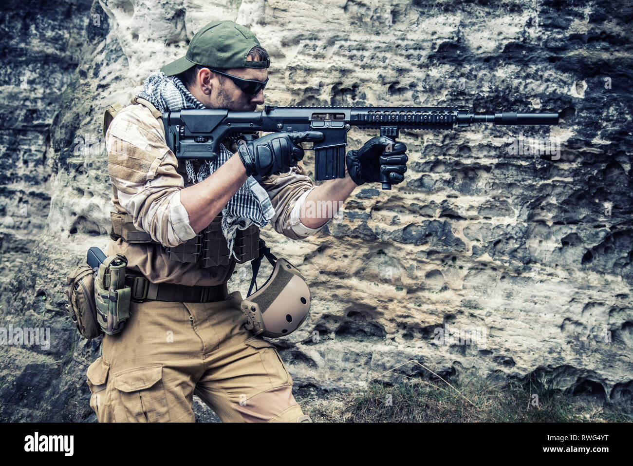 Private military contractor in baseball cap with assault rifle in the ...