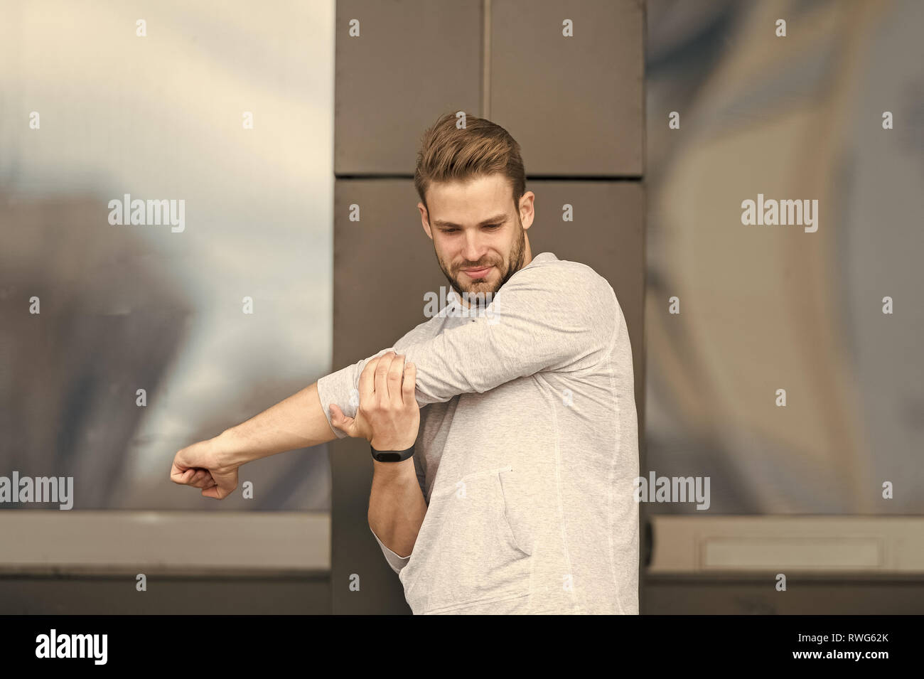 Man athlete concentrated face stretching arms before workout, urban ...