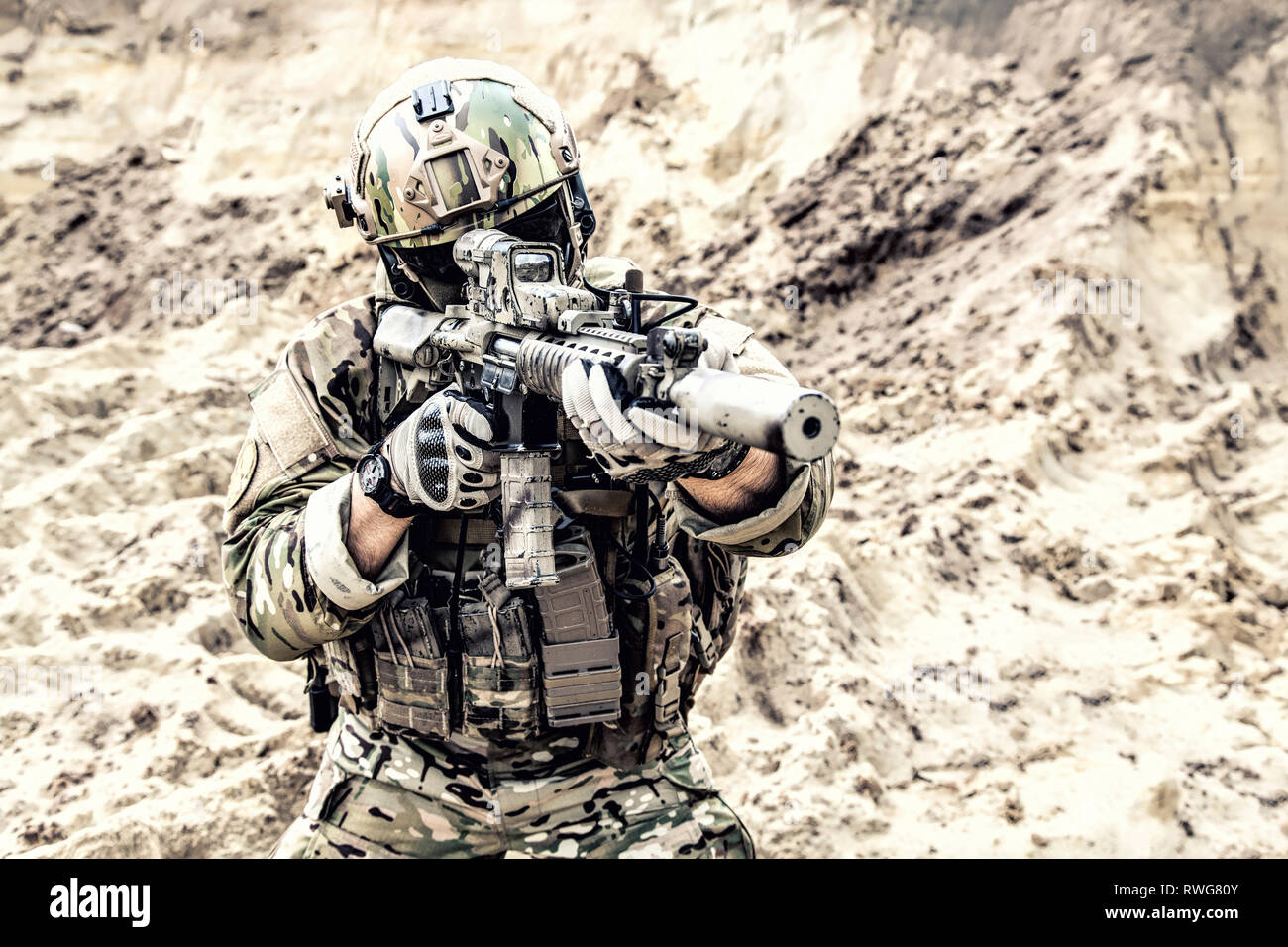 Soldier aiming a carbine assault rifle in a desert area of the Middle ...
