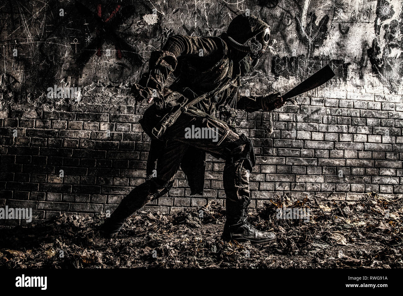 Post apocalyptic survivor running along a brick wall with graffiti in a ...