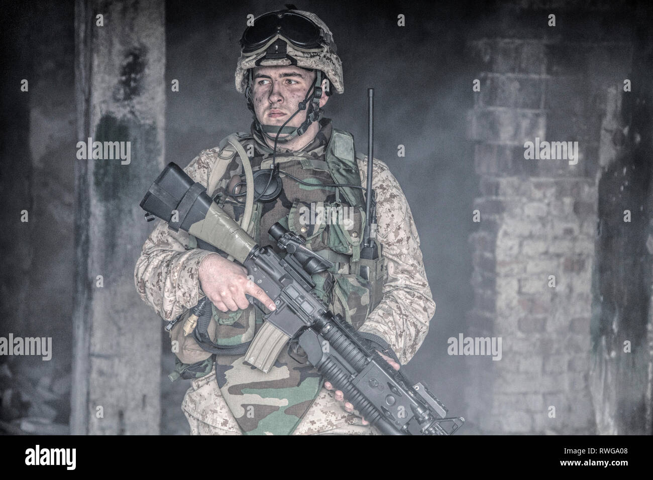 U.S. Marine equipped with tactical radio and service rifle in a smoky ...
