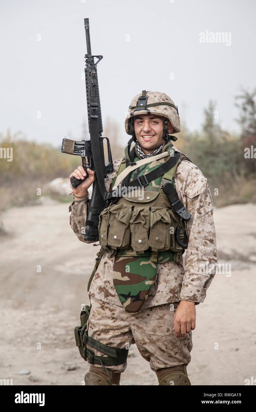 Portrait of smiling U.S. soldier posing with assault rifle while ...