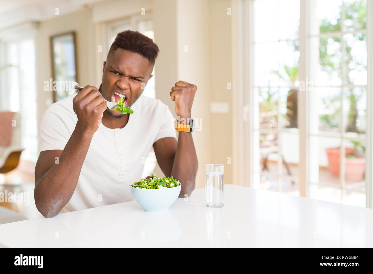 African american man eating fresh healthy salad annoyed and frustrated ...