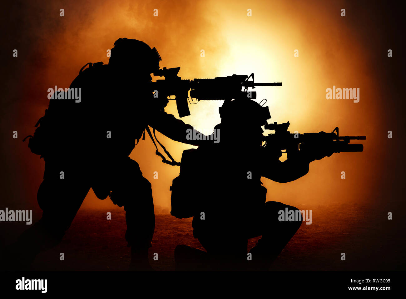 Silhouette of two soldiers attacking enemy while surrounded by fire and ...