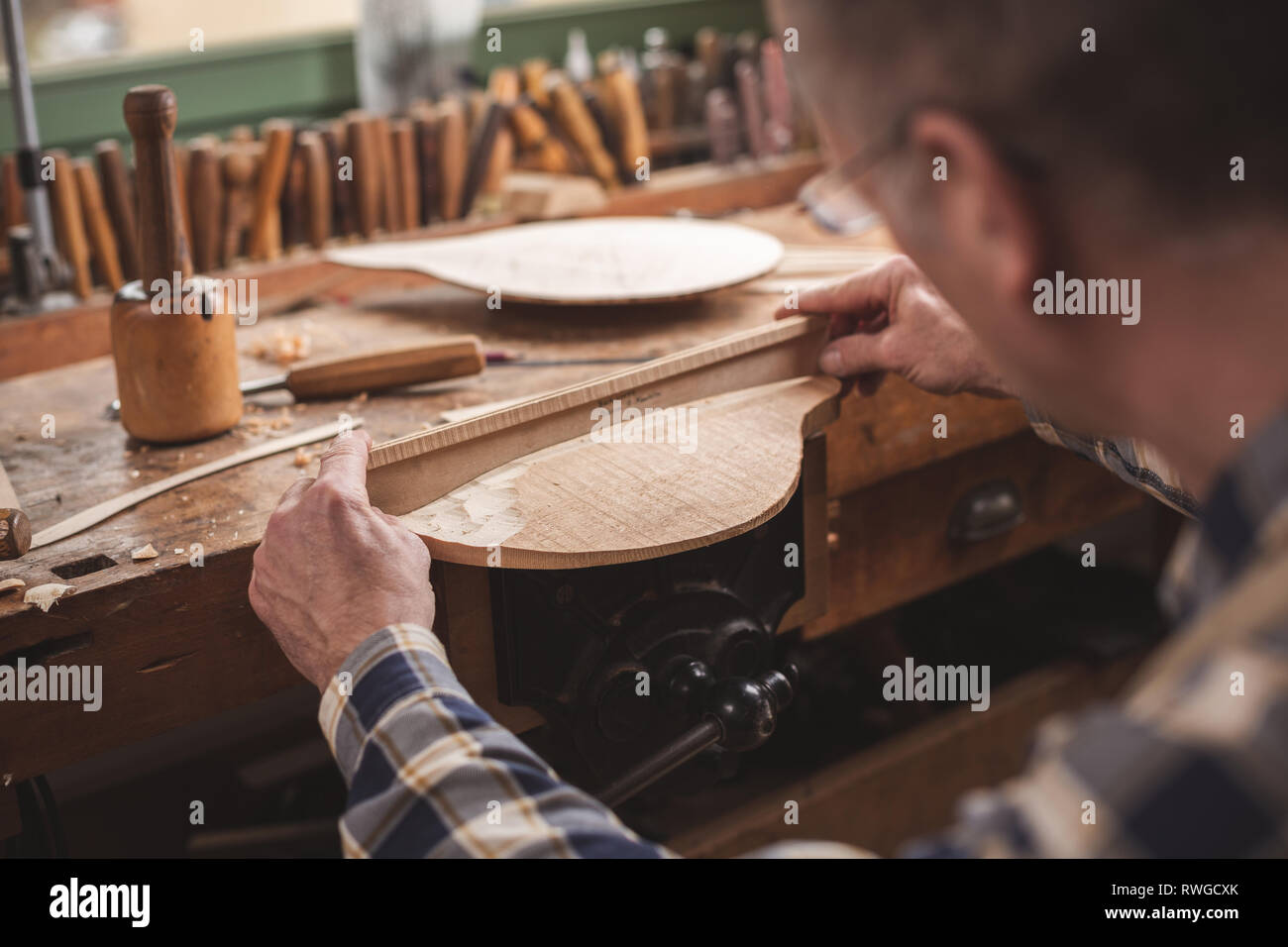 Over shoulder view of an instrument maker observing his workpiece with ...